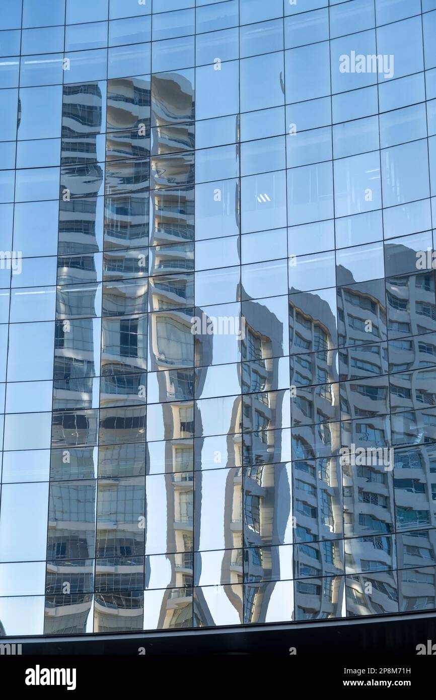 A reflection of modern city buildings in the glass facade of a tall ...