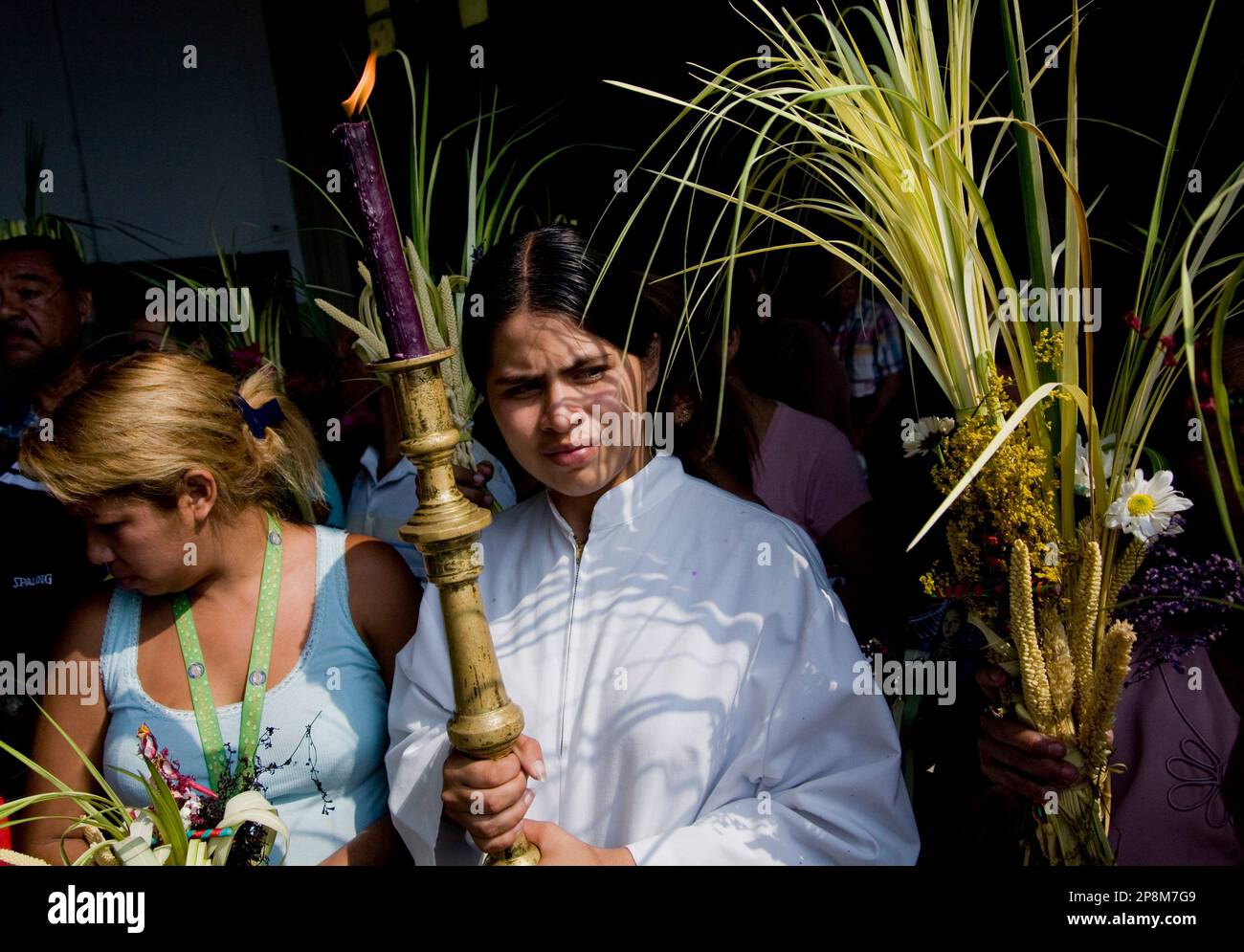 A woman holds a candle during Palm Sunday celebrations in San Salvador ...