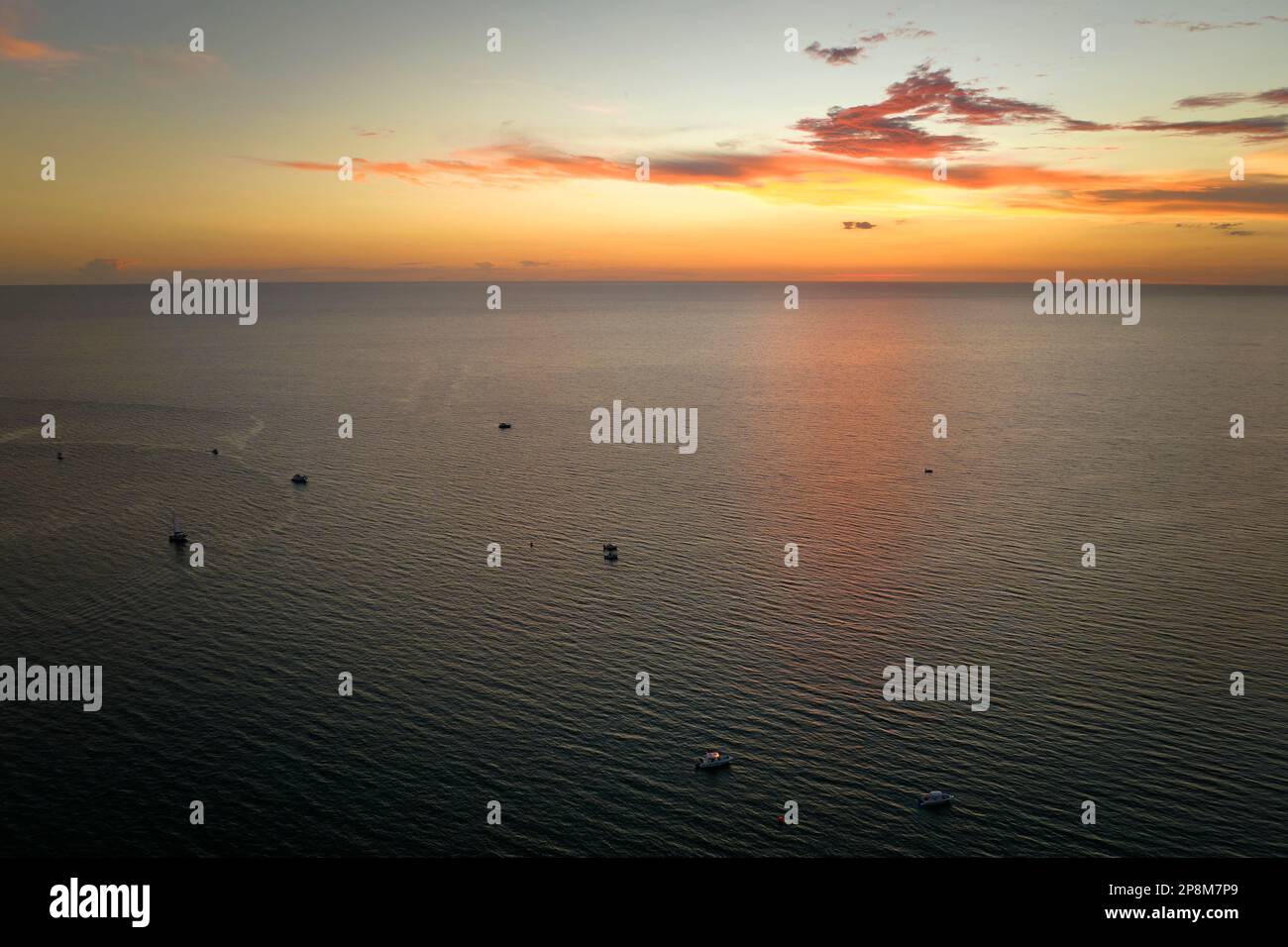 Aerial view of small yachts at sunset floating on sea waves with ripple ...