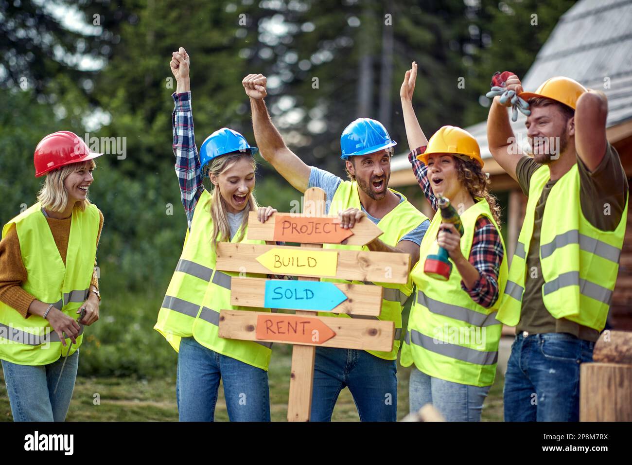 A group of cheerful both female and male builders posing for a photo at ...