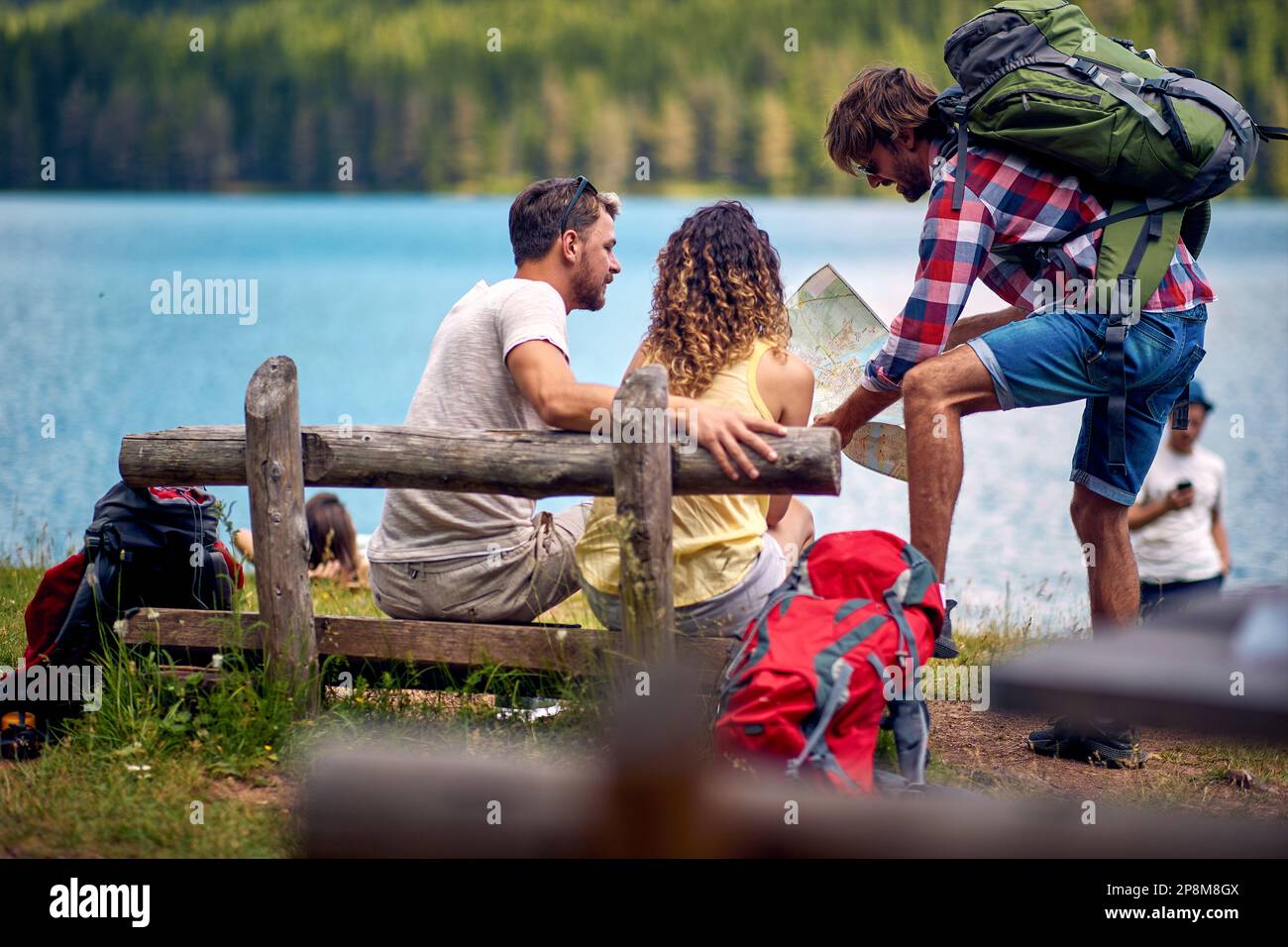 group of caucasian people taking a break in nature, looking at the map ...