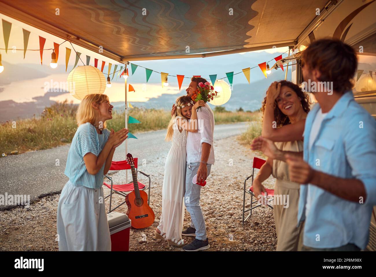young caucasian couple having outdoor engagement with friends around ...