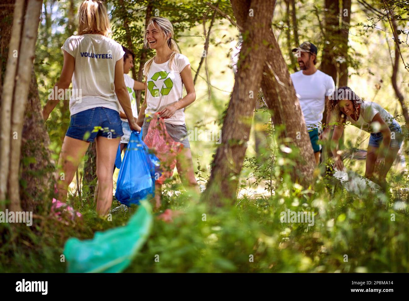 Group of friends in forest picking up trash. Man and woman doing ...
