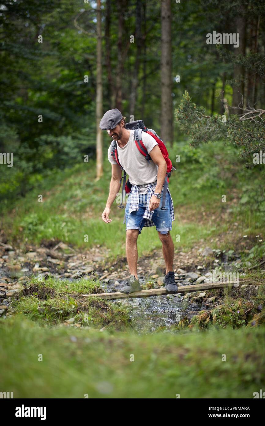 Young man Crossing River.Journey in the forest Stock Photo - Alamy