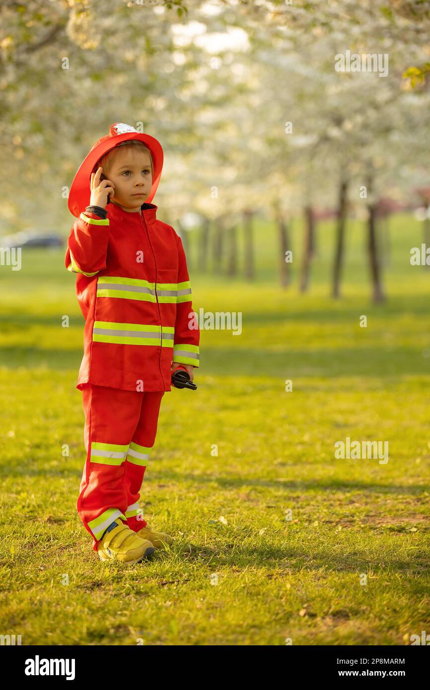 Little toddler child with fireman costume in park, pretending to be ...