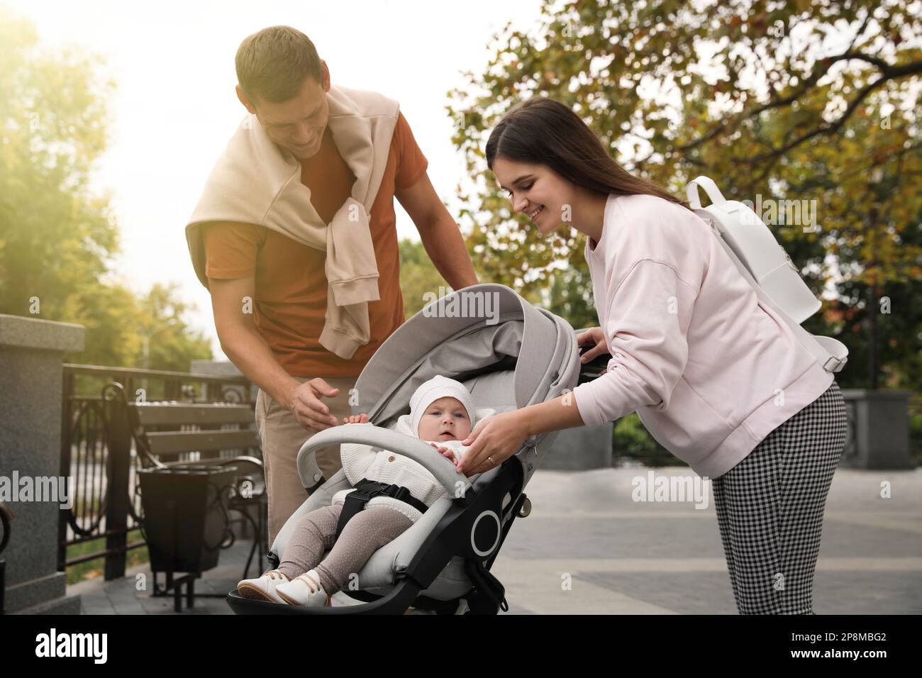 Happy parents walking with their adorable baby in stroller outdoors ...