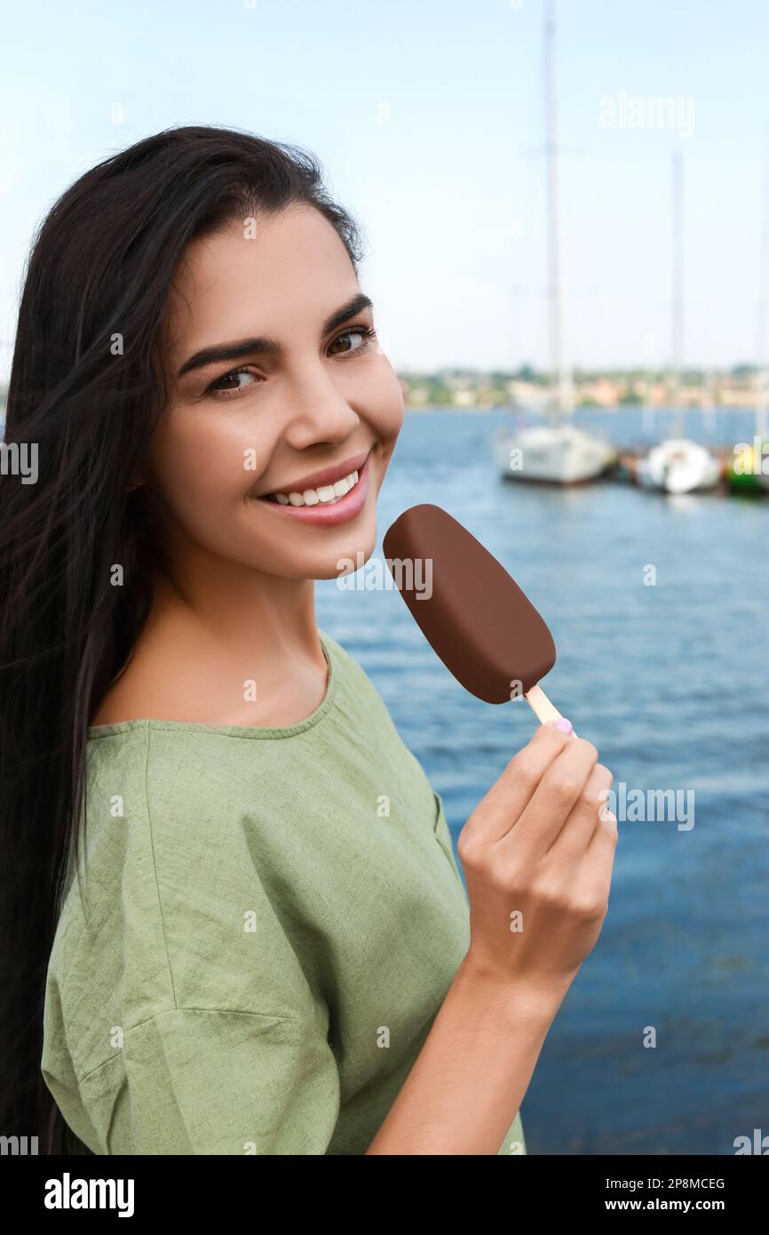 Beautiful Young Woman Holding Ice Cream Glazed In Chocolate Near River
