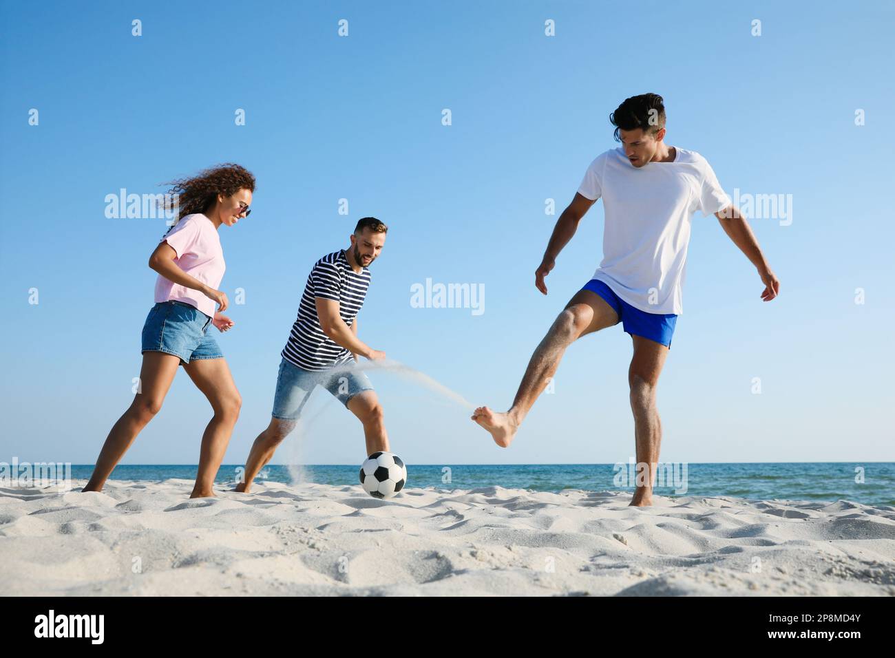 Group of friends playing football on beach Stock Photo - Alamy
