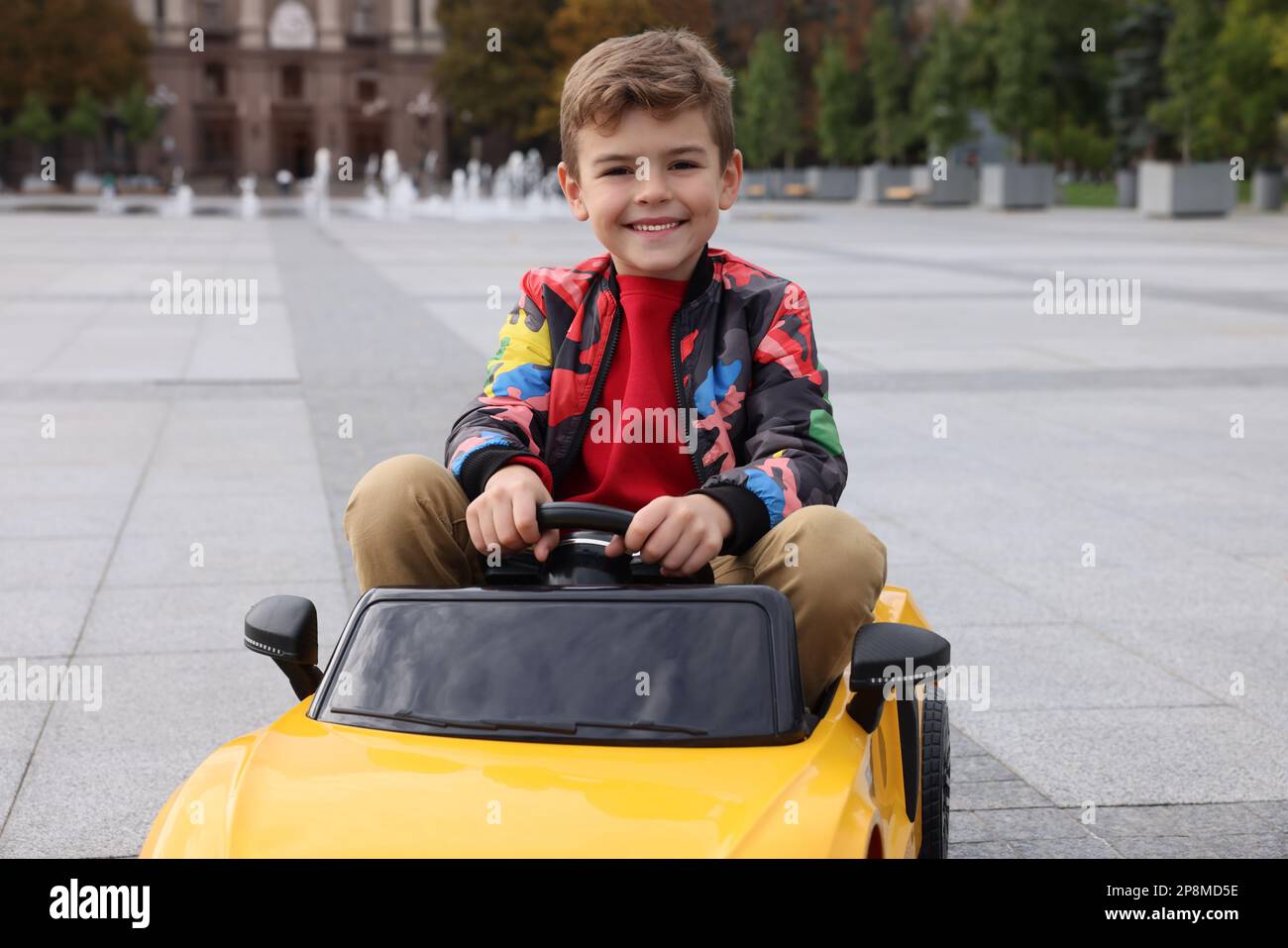 Cute little boy driving children's car on city street Stock Photo - Alamy