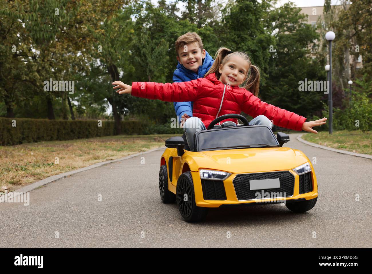 Cute boy pushing children's car with little girl outdoors. Space for ...