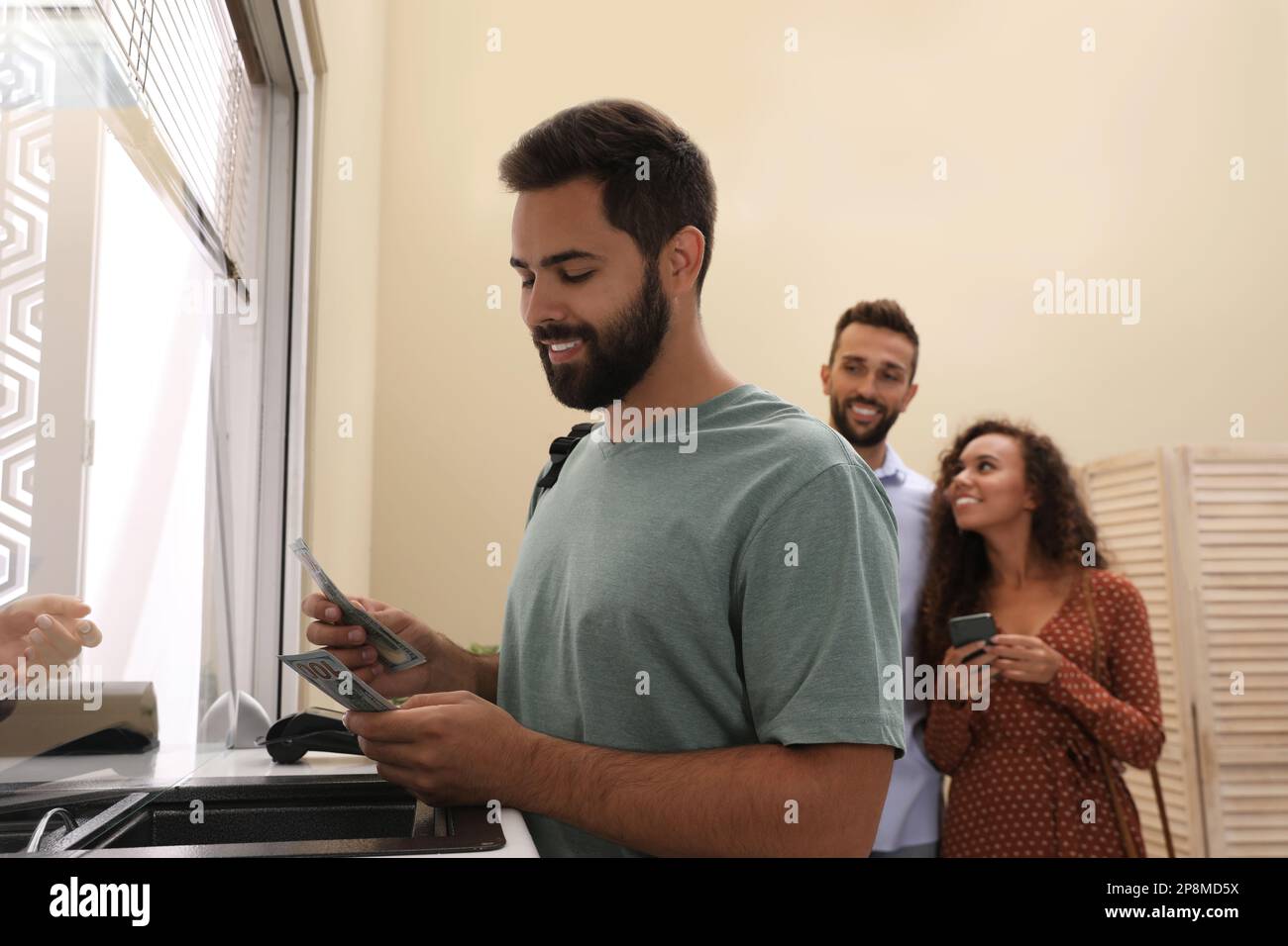 Man with money at cash department window in bank. Currency exchange ...