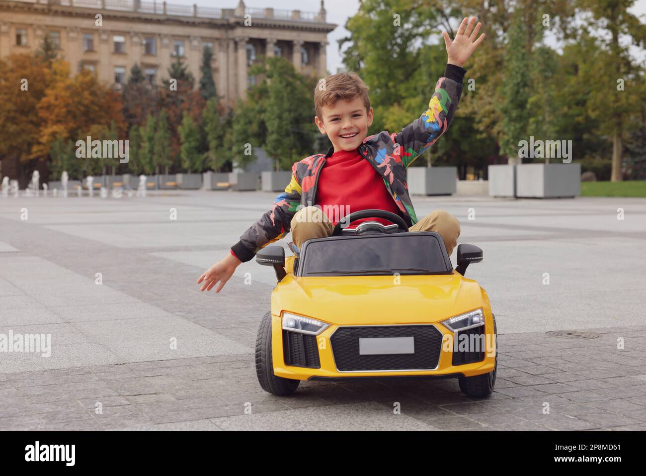 Cute little boy driving children's car on city street Stock Photo - Alamy