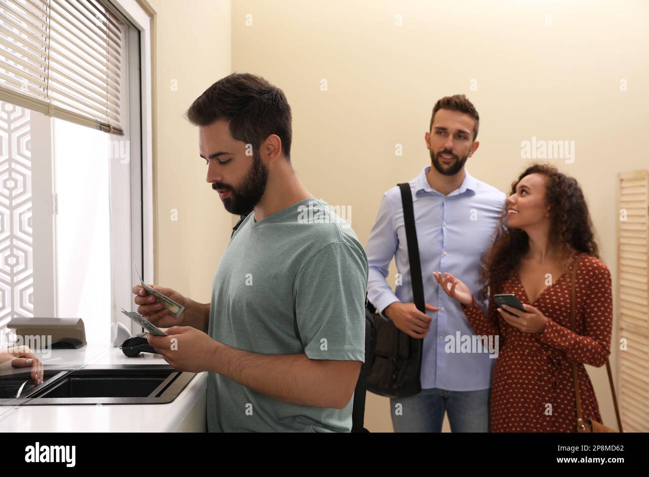 Man with money and other people in line at cash department window ...