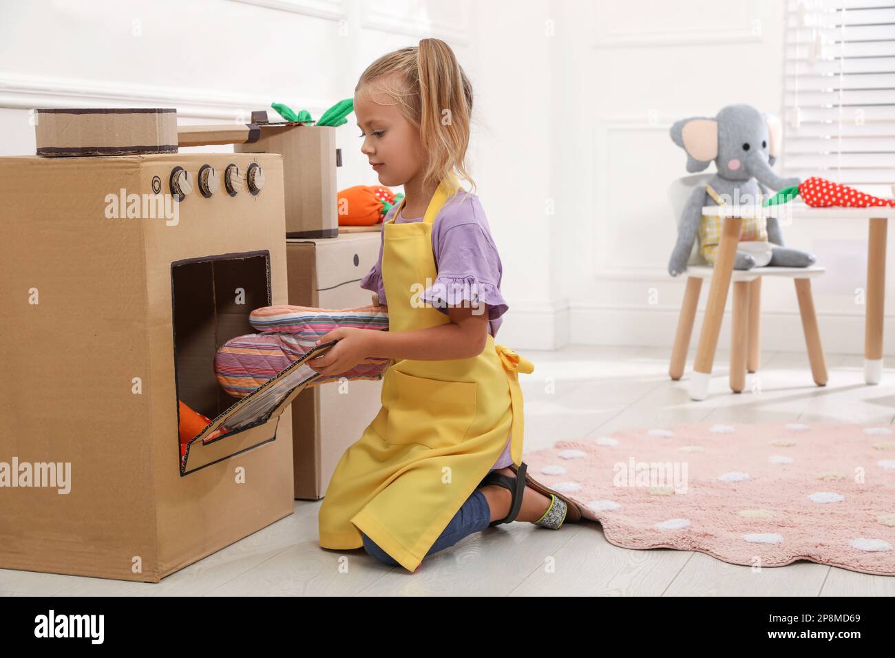 Little girl playing with toy cardboard oven at home Stock Photo - Alamy