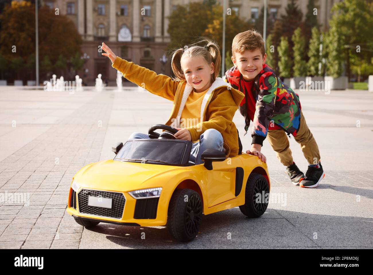 Cute boy pushing children's car with little girl outdoors on sunny day ...