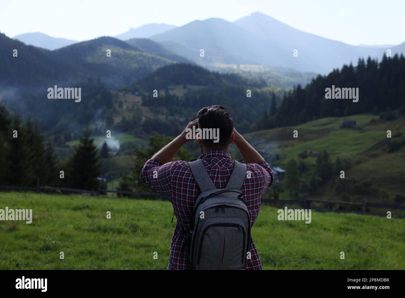 Tourist with backpack and binoculars enjoying landscape in mountains ...