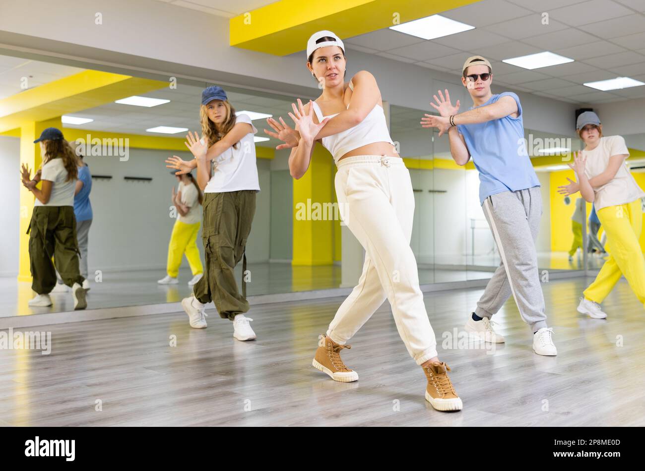 Group of young active tween dancers in casual wear moving with crossed ...