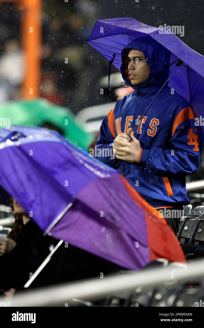 Fans look on during a rain delay in the sixth inning of an exhibition ...