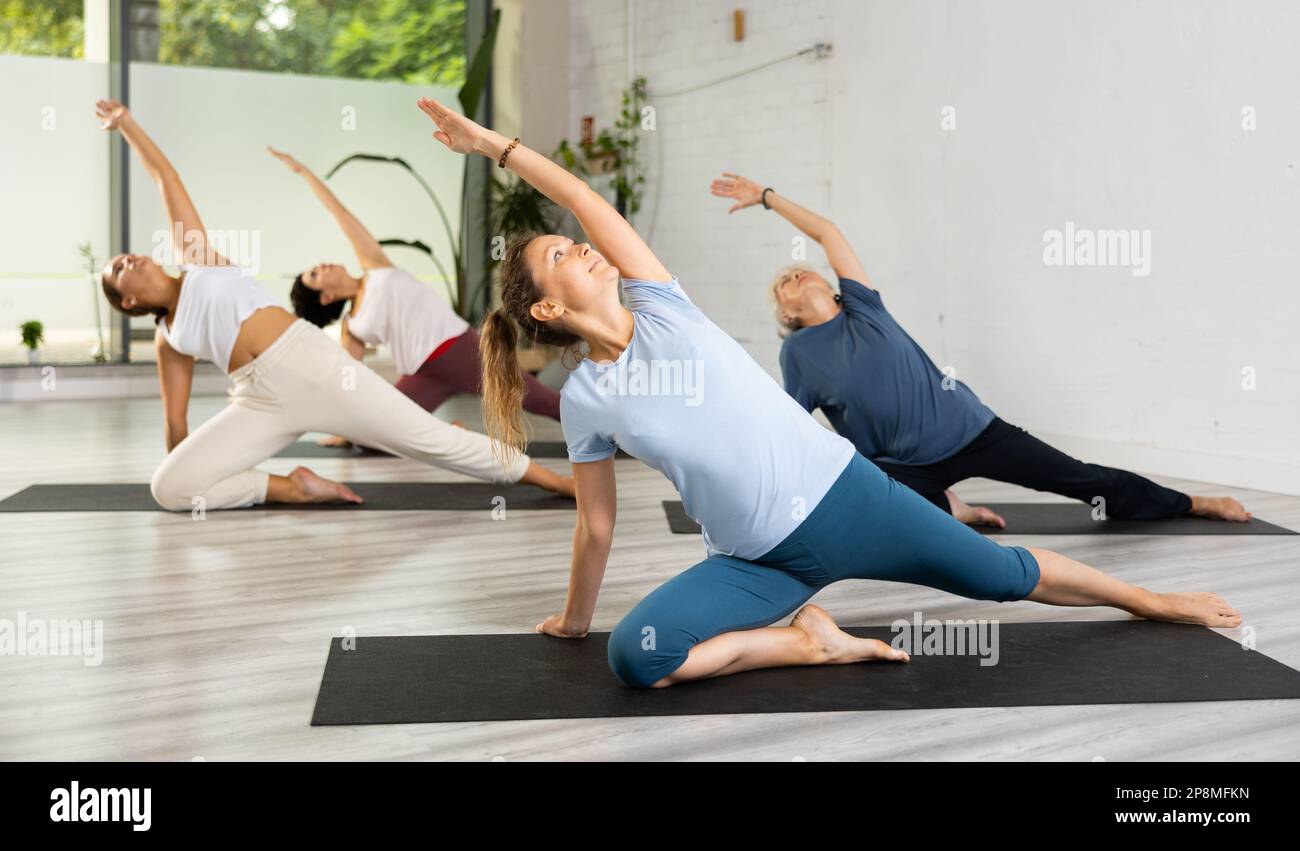 Group of young active different ages women doing stretching exercises ...