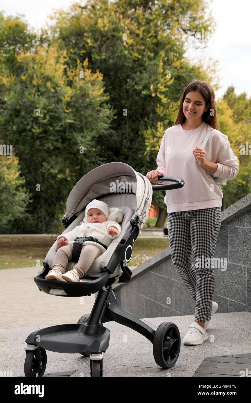Young mother walking with her adorable baby in stroller outdoors Stock ...