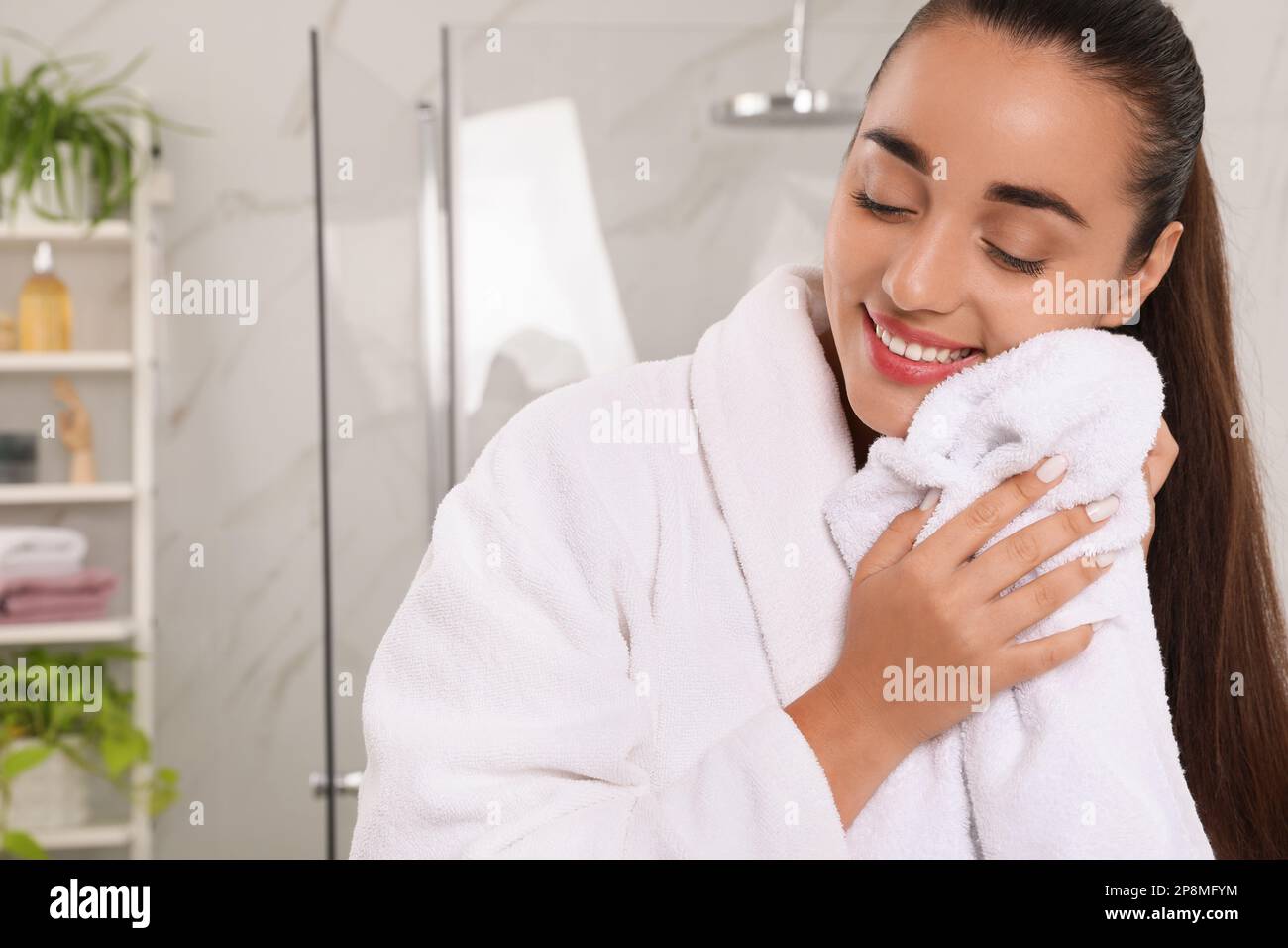 Beautiful young woman wiping face with towel in bathroom. Facial wash ...