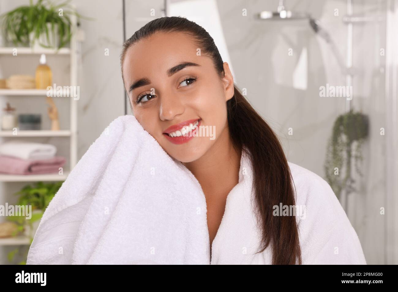 Beautiful young woman wiping face with towel in bathroom. Facial wash ...