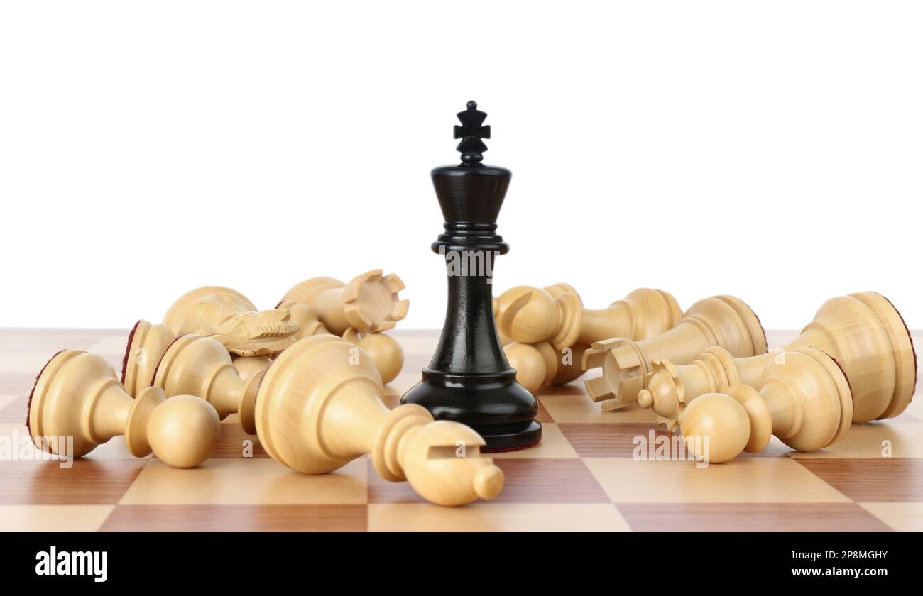 King among fallen chess pieces on wooden board against white background ...