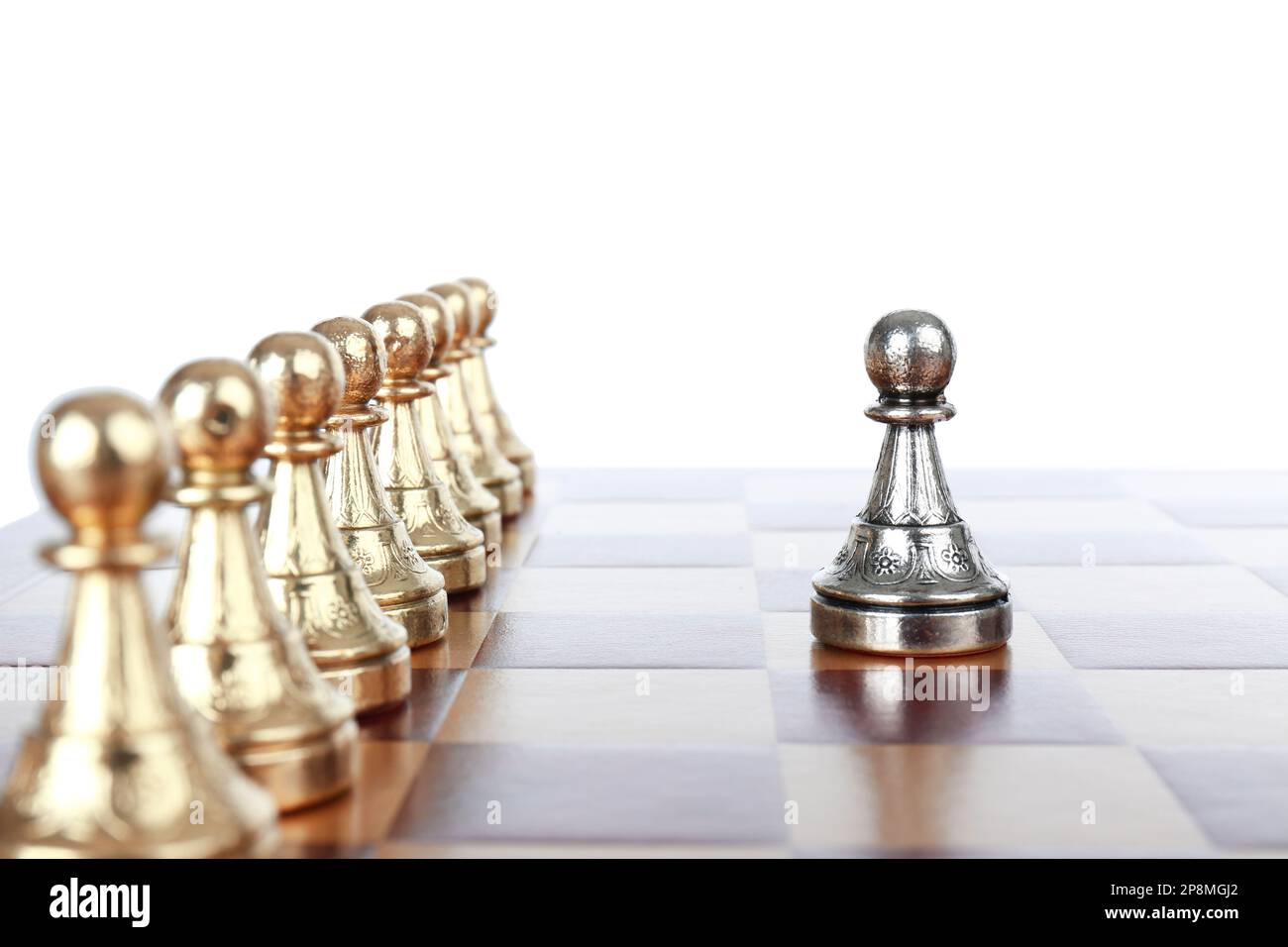 Silver pawn in front of golden ones on wooden chess board against white ...