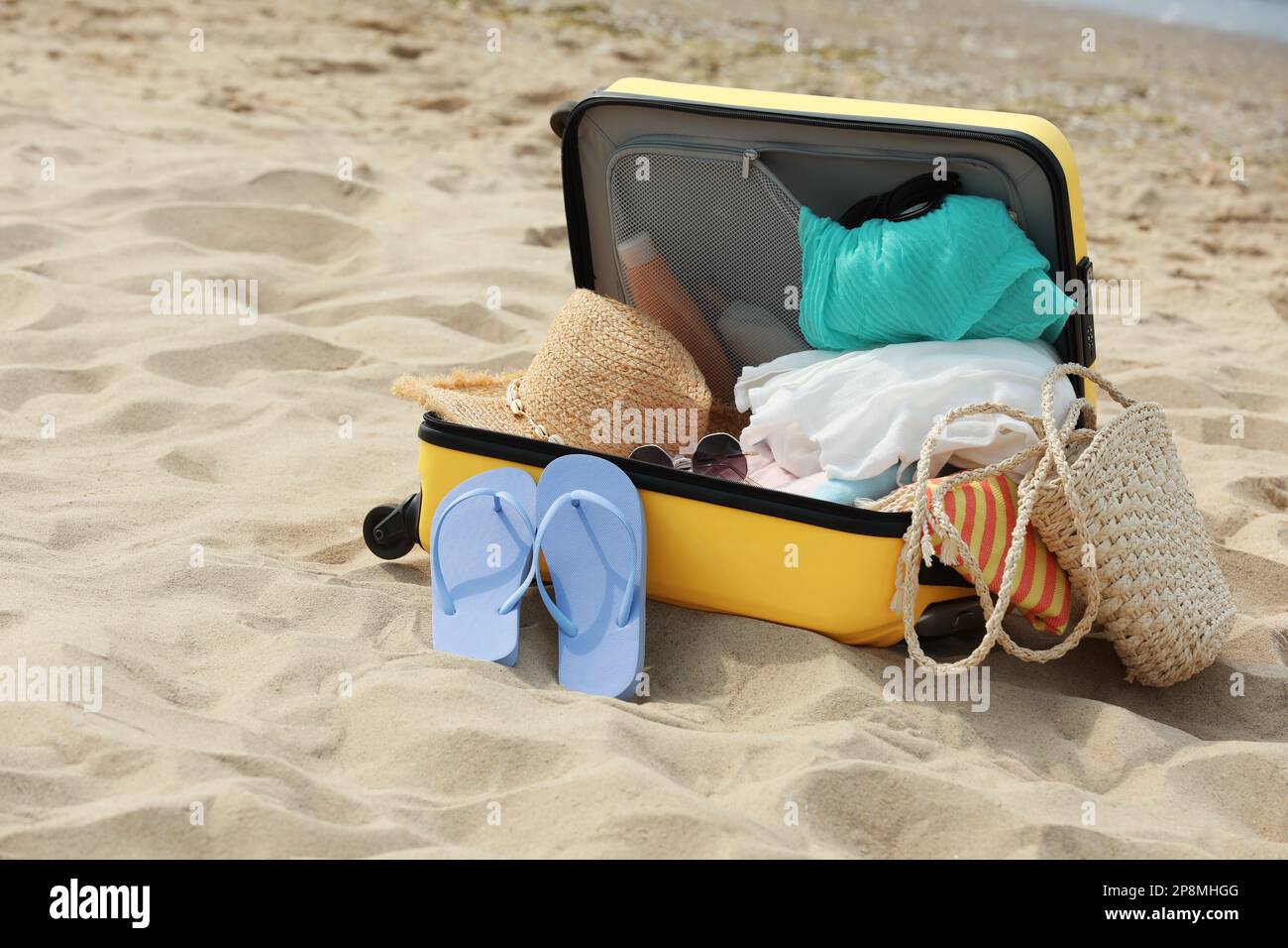 Open suitcase with beach items on sandy coast Stock Photo - Alamy