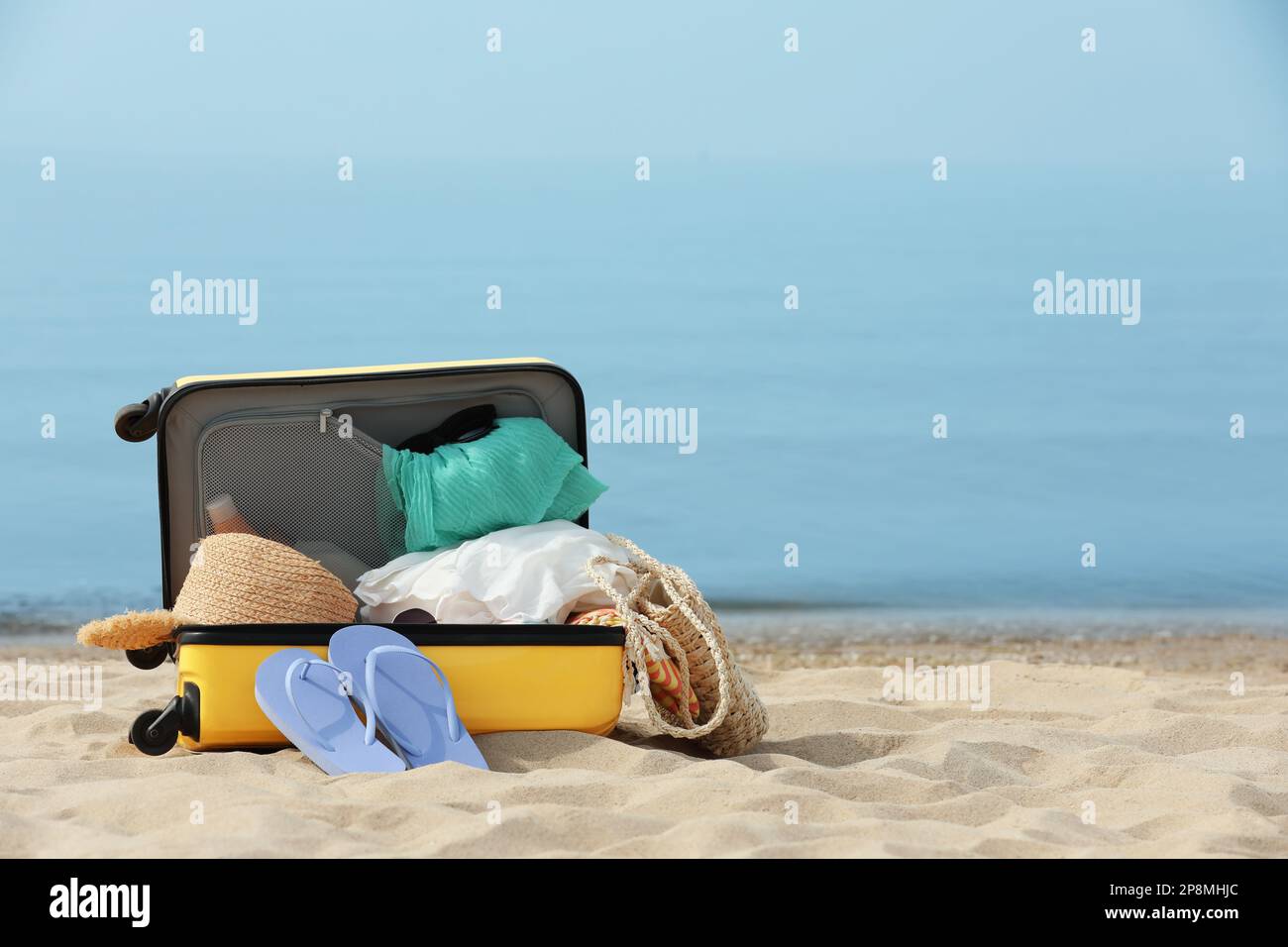 Open suitcase with beach items on sandy seashore, space for text Stock ...
