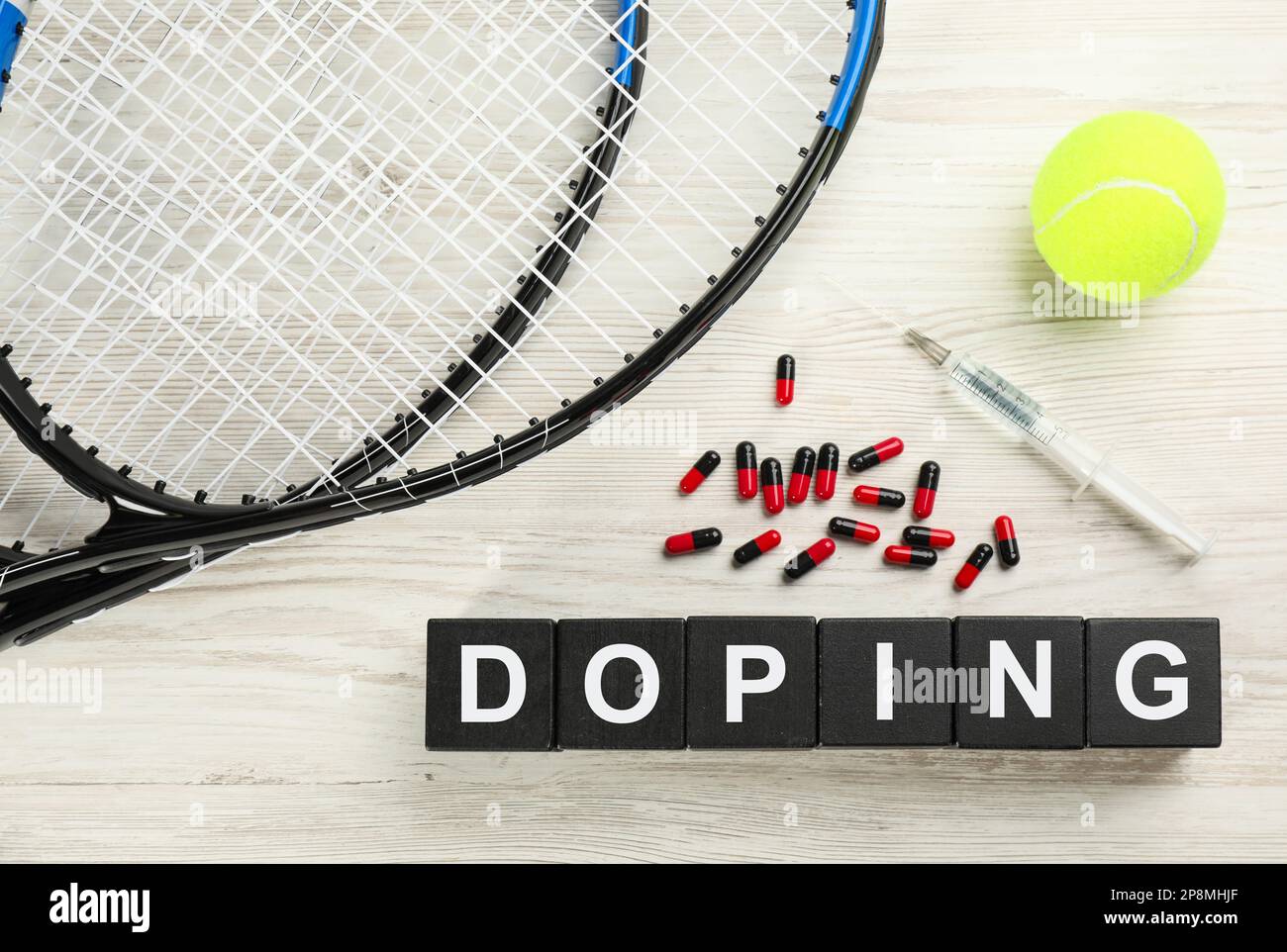 Black cubes with word Doping, tennis rackets, ball and drugs on white ...