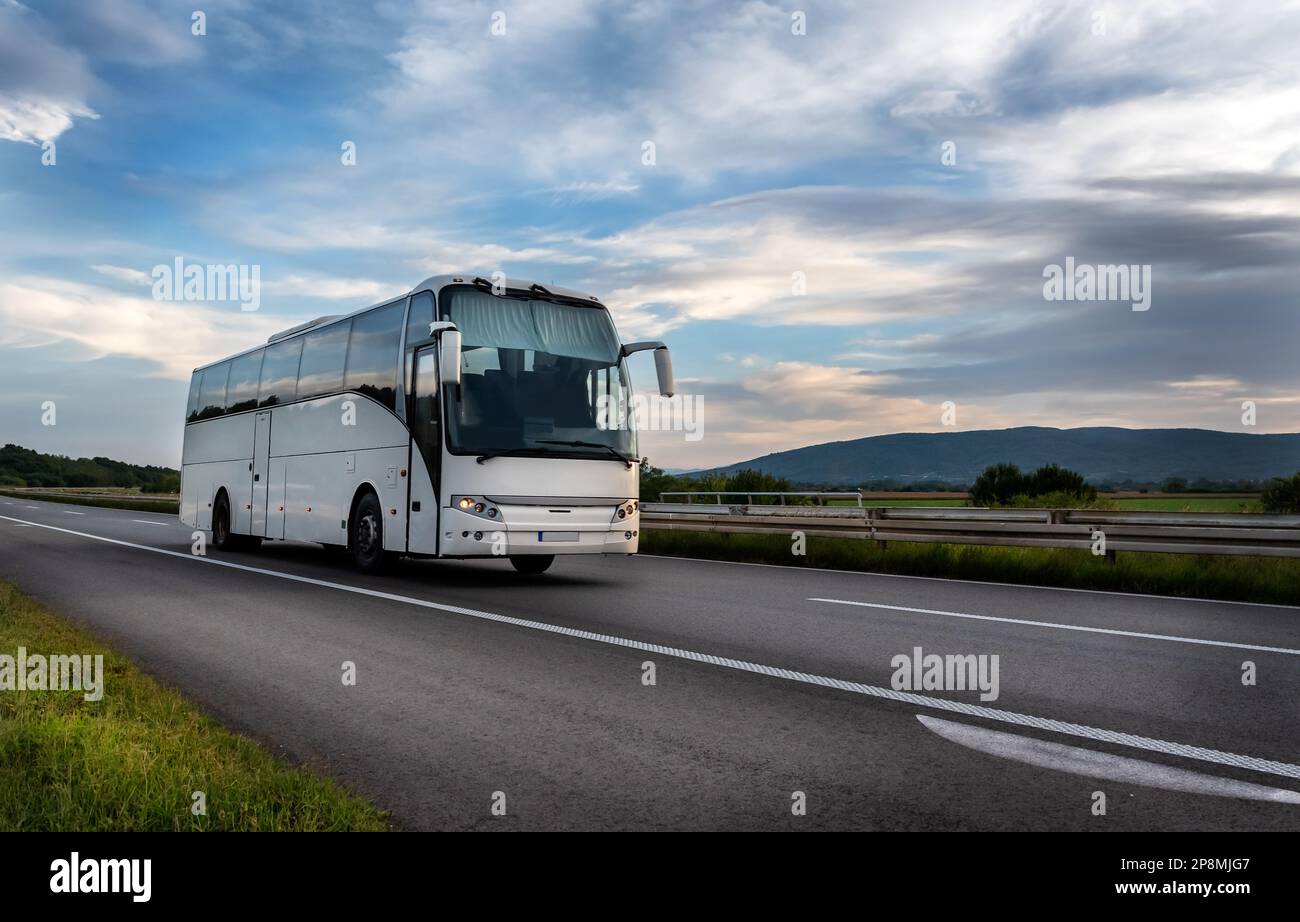 White Modern comfortable tourist bus driving through highway at bright ...