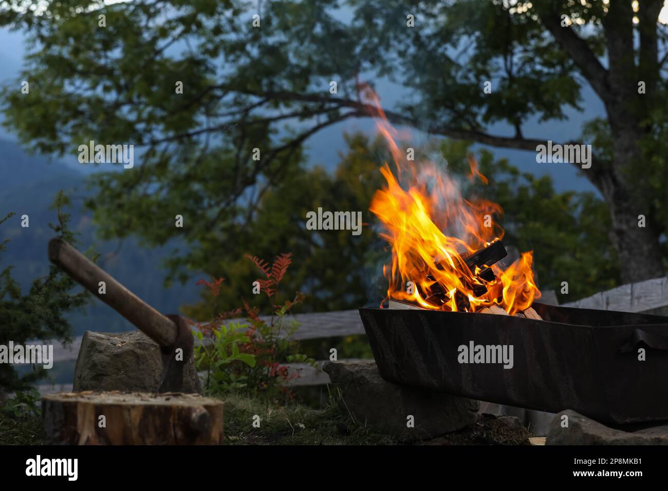 Metal brazier with burning firewood on backyard in mountains Stock ...