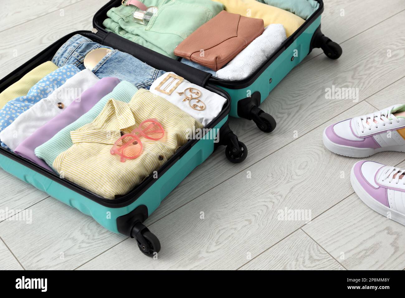 Open suitcase packed for trip and shoes on floor Stock Photo - Alamy