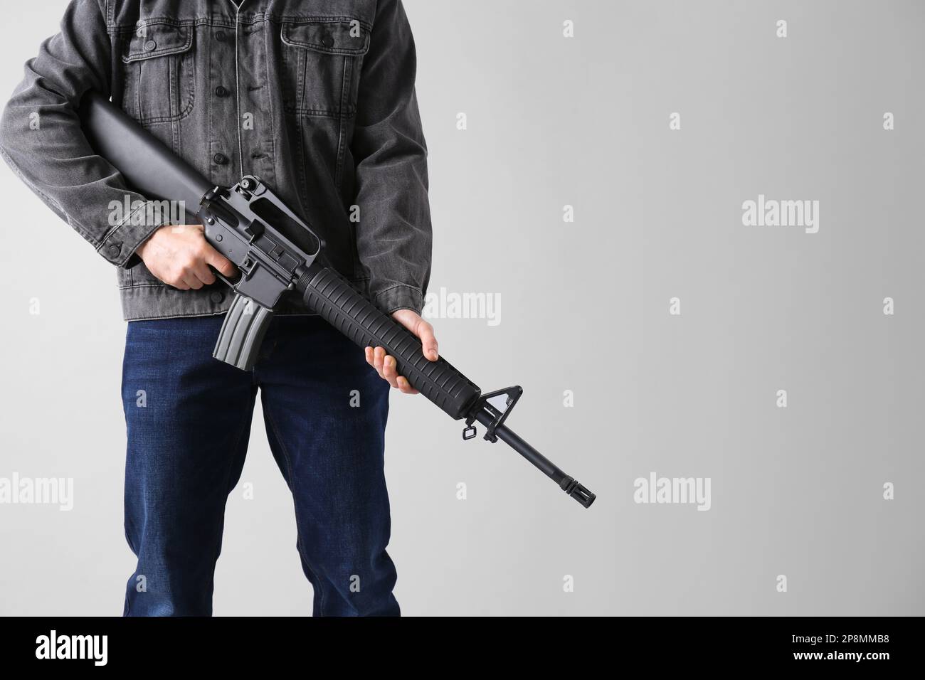 Assault gun. Man holding rifle on light background, closeup. space for ...