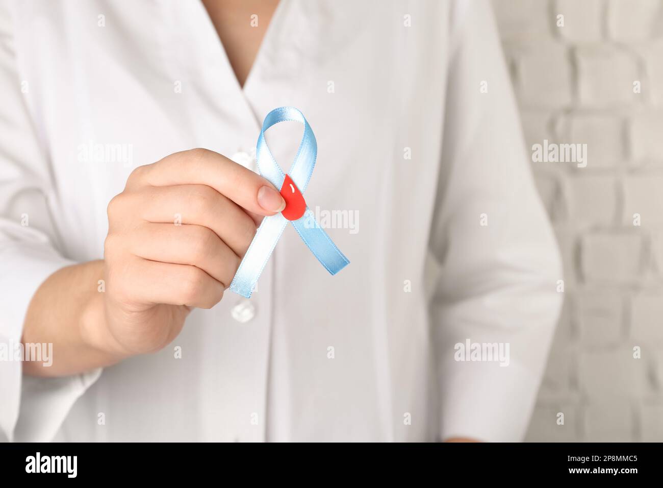 Doctor holding light blue ribbon with paper blood drop, closeup. World ...