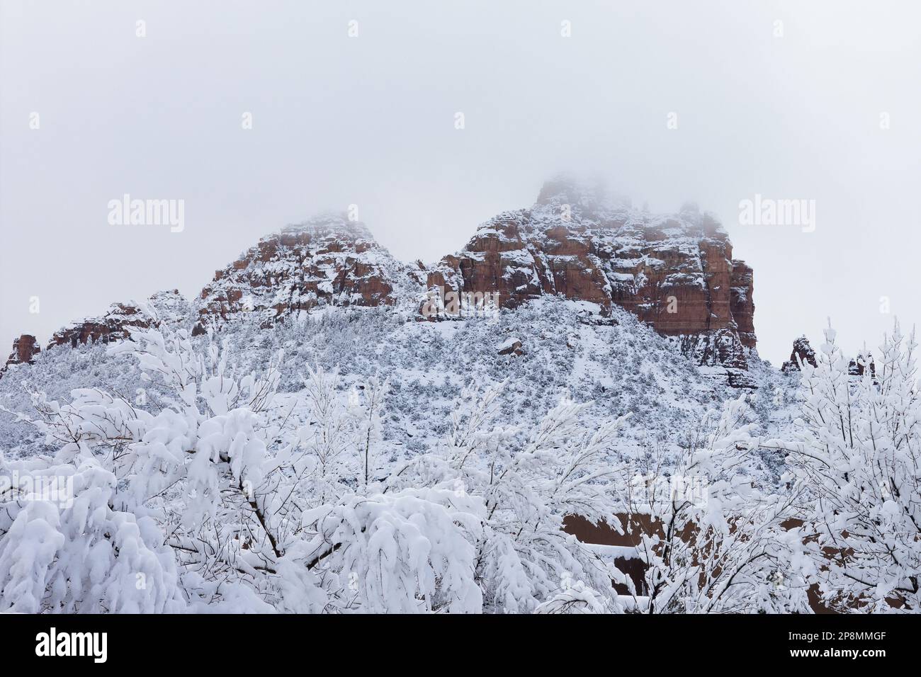 View of beautiful red rock mountains shrouded in mist during a snow ...
