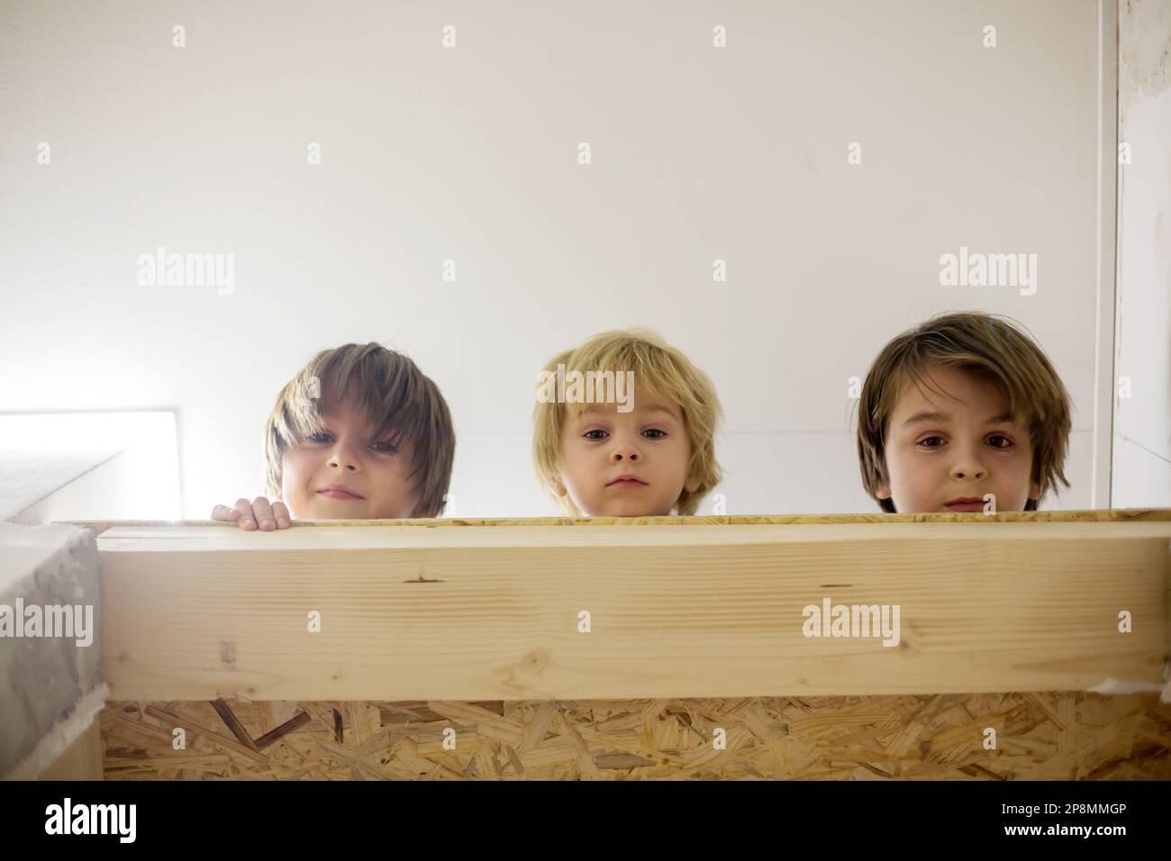 Three children, boy brothers, lying down in a narrow gap over the doors ...