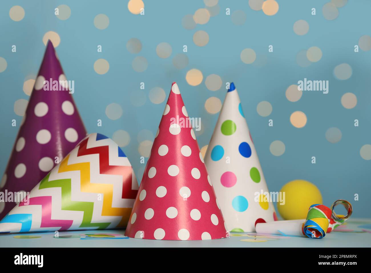 Colorful party hats and festive items on table against blue background ...