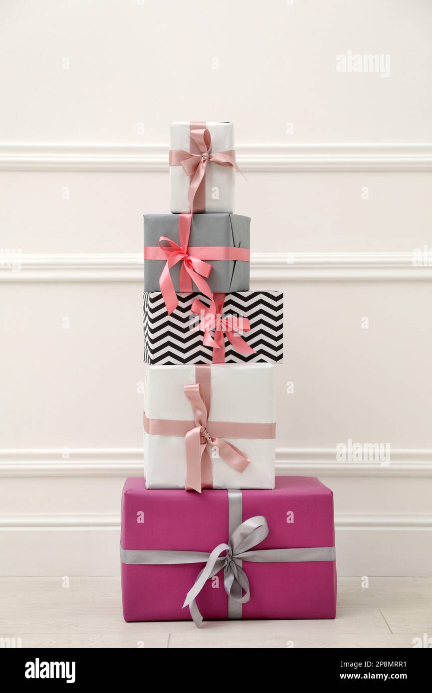 Many gift boxes with colorful bows near white wall Stock Photo - Alamy