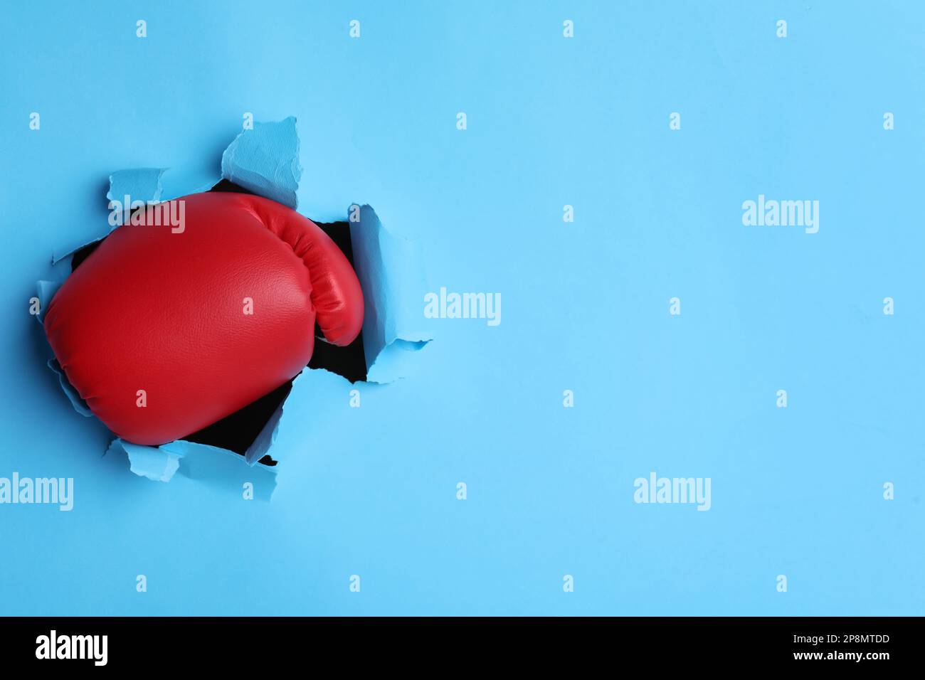 Man breaking through light blue paper with boxing glove, closeup. Space ...