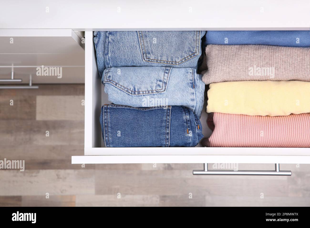 Open drawer with folded clothes indoors, top view. Vertical storage ...