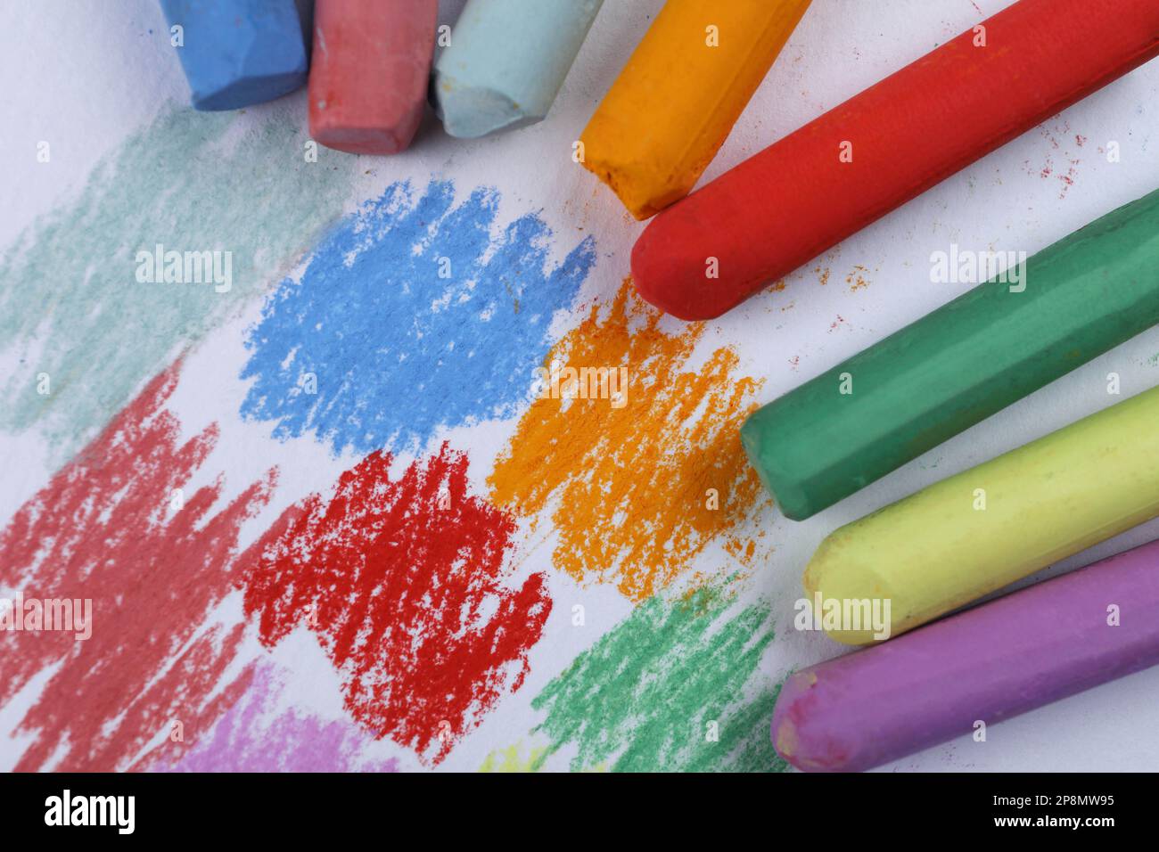 Colorful pastel chalks and scribbles on white background, flat lay ...