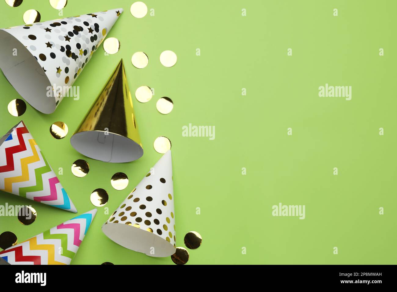 Bright party hats and shiny confetti on light green background, flat ...