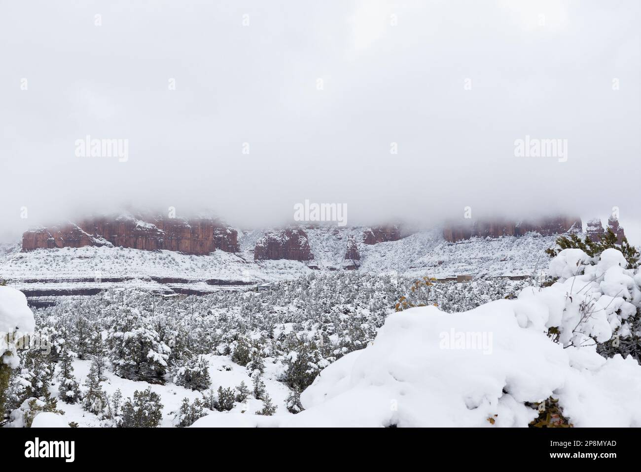 View of beautiful red rock mountains shrouded in mist during a snow ...