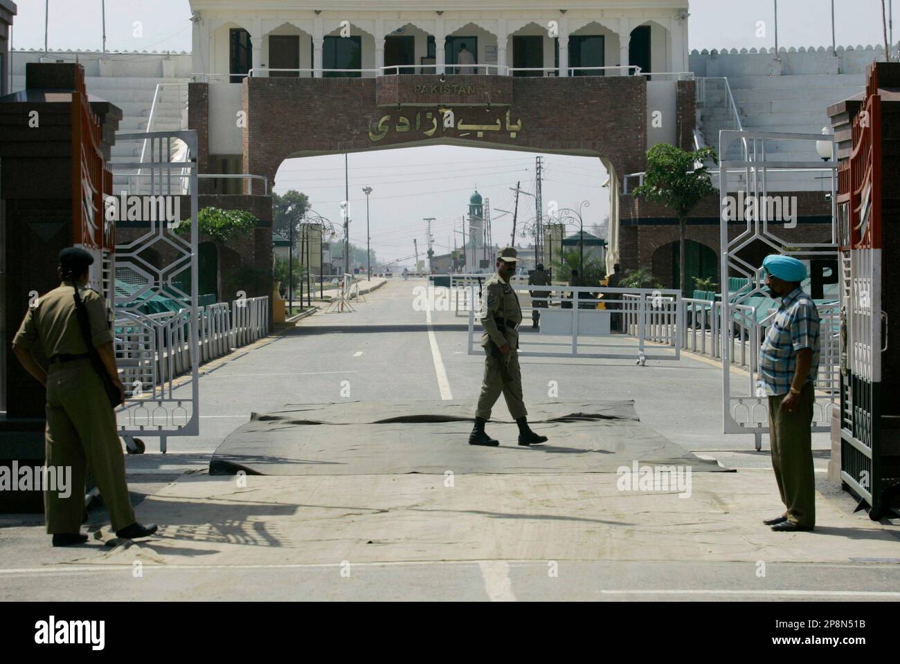 An Indian Border Security Force soldier stands guard, left, as a ...