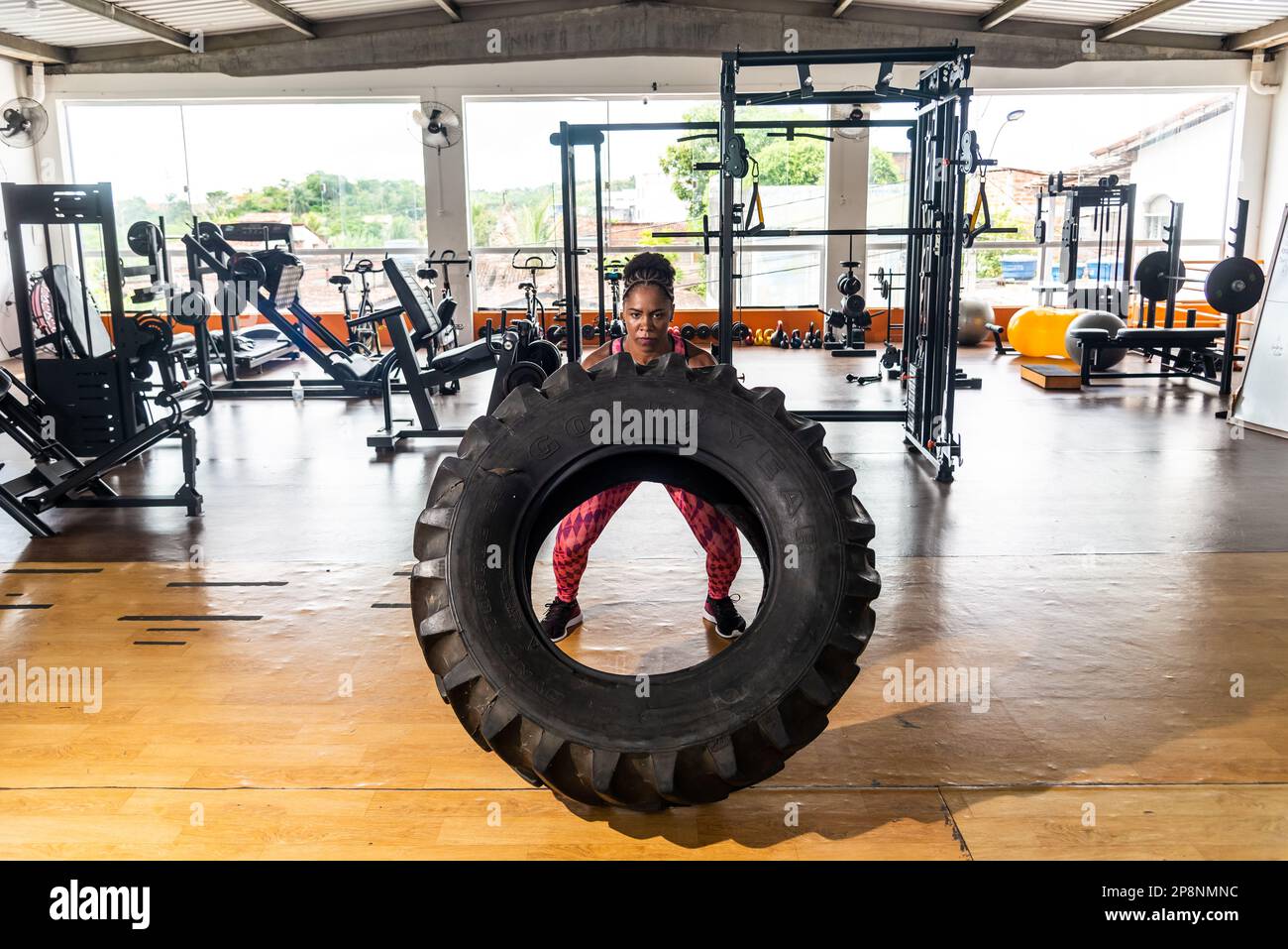 Young strong woman lifting tire for strength training. Fitness exercise ...