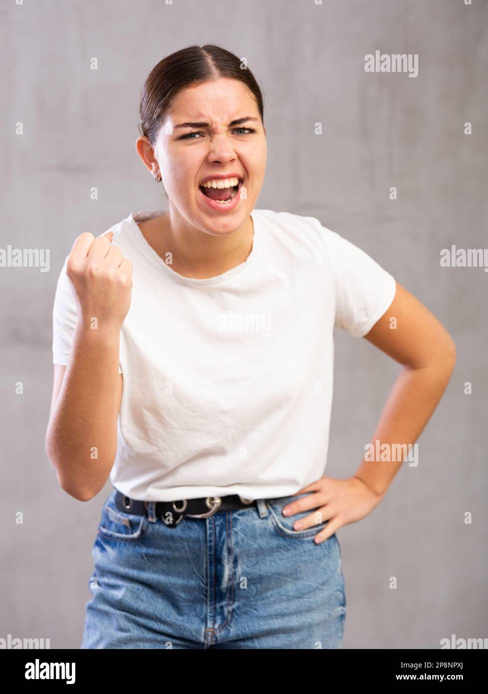 Aggressive young woman standing against unicoloured background Stock ...