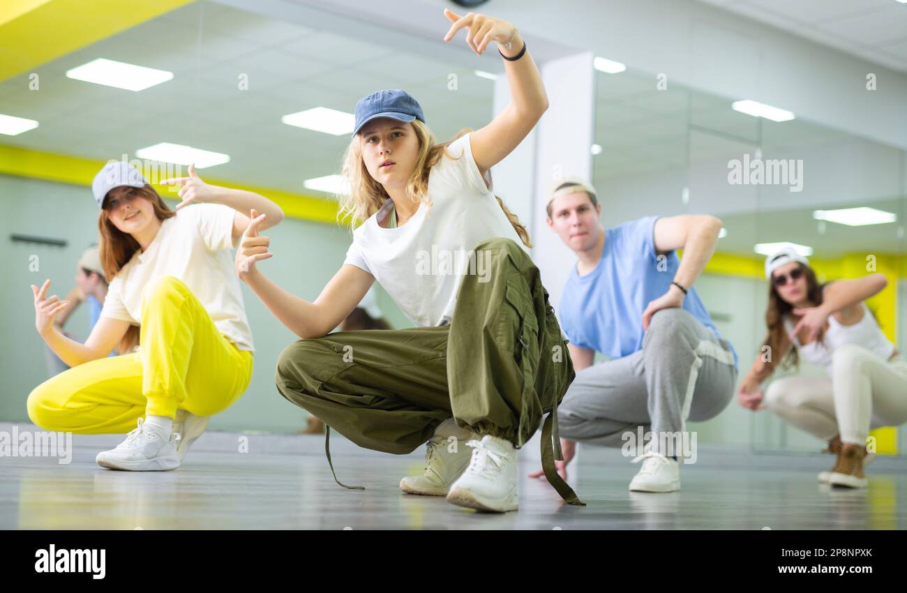 Teenage girl sitting in breakdance pose in dance hall Stock Photo - Alamy