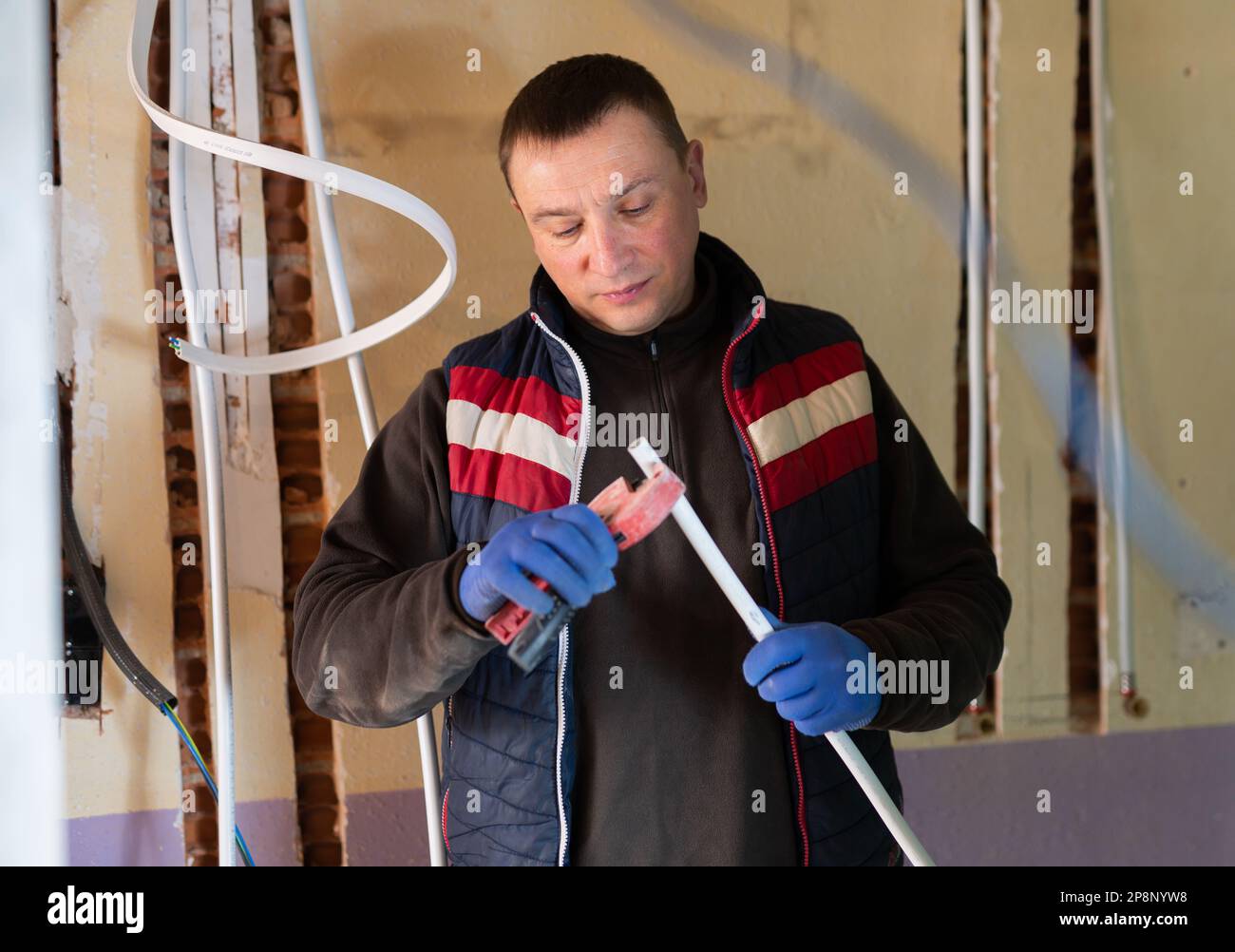Plumber installs new plastic pipes in house under construction Stock ...